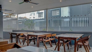 Restaurante com mesas ao ar livre, grandes janelas e vista para edifícios.