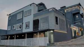 Um edifício moderno de dois andares com telhado plano, janelas grandes e uma varanda.