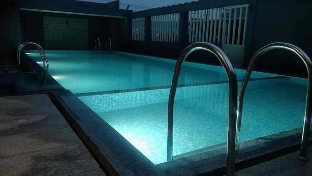 Piscina com água cristalina e corrimãos de metal.