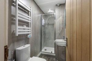 Uma casa de banho moderna com cabine de duche em vidro, sanita e lavatório.