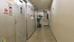 Corredor com elevador de metal, um vaso de planta e um extintor de incêndio.