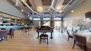 Espaçoso bar com piano, assentos e balcão repleto de garrafas.