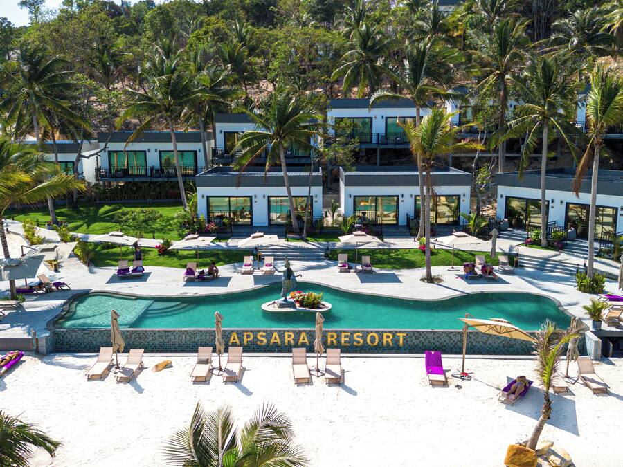 Um resort com piscina, espreguiçadeiras e palmeiras.