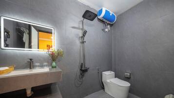 Casa de banho moderna com um espelho grande, um chuveiro, uma sanita e lavatório com um vaso de flores.