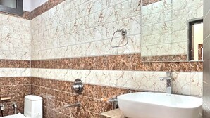 Um banheiro moderno com detalhes em mármore, pia, vaso sanitário e chuveiro.
