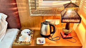 Bandeja de café da manhã bem organizada com chaleira, xícaras e um pequeno prato de petiscos sobre uma mesa de madeira.
