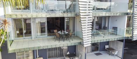 Um edifício moderno de dois andares com varanda de vidro, área de estar externa e vista da região circundante.