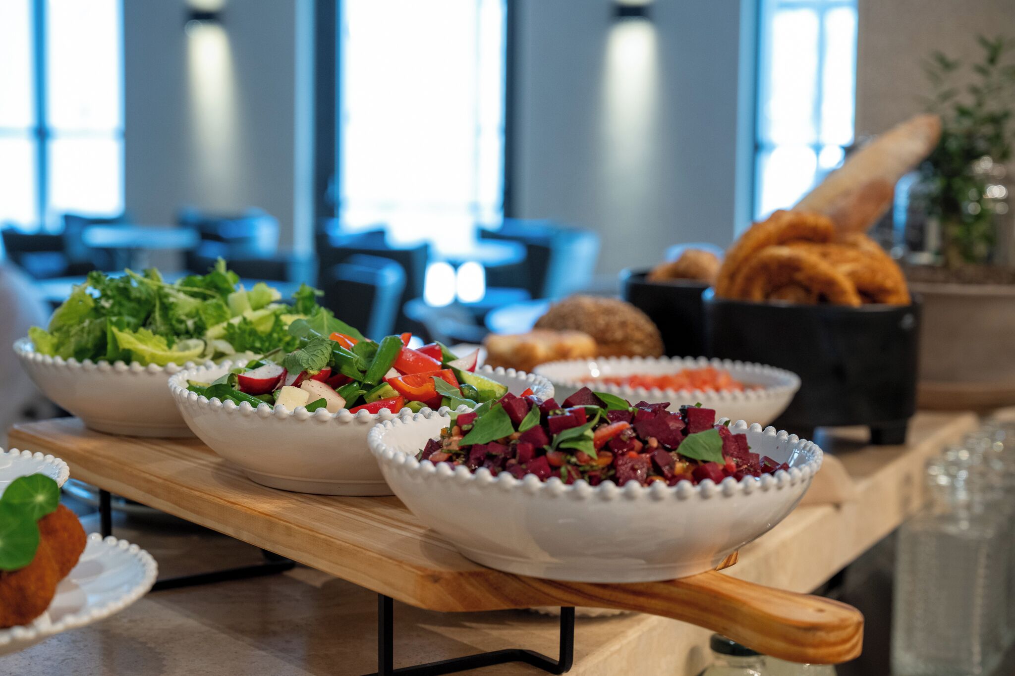 Uma mesa de buffet com saladas e pães variados.