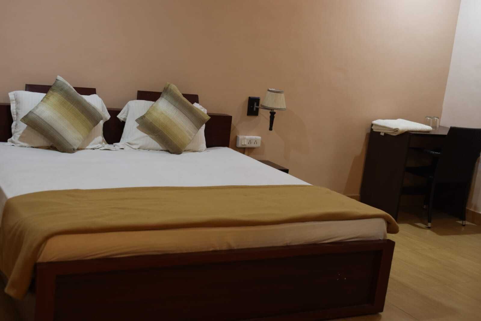 Quarto de hotel com cama, escrivaninha e luminária.
