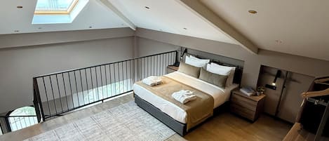 Quarto moderno com claraboia, cama grande, mesa de cabeceira e banheira.