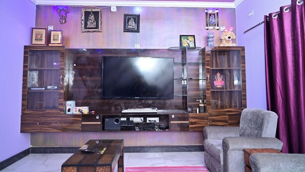 Uma sala de estar com uma televisão de tela plana grande, armários de madeira e um sofá.