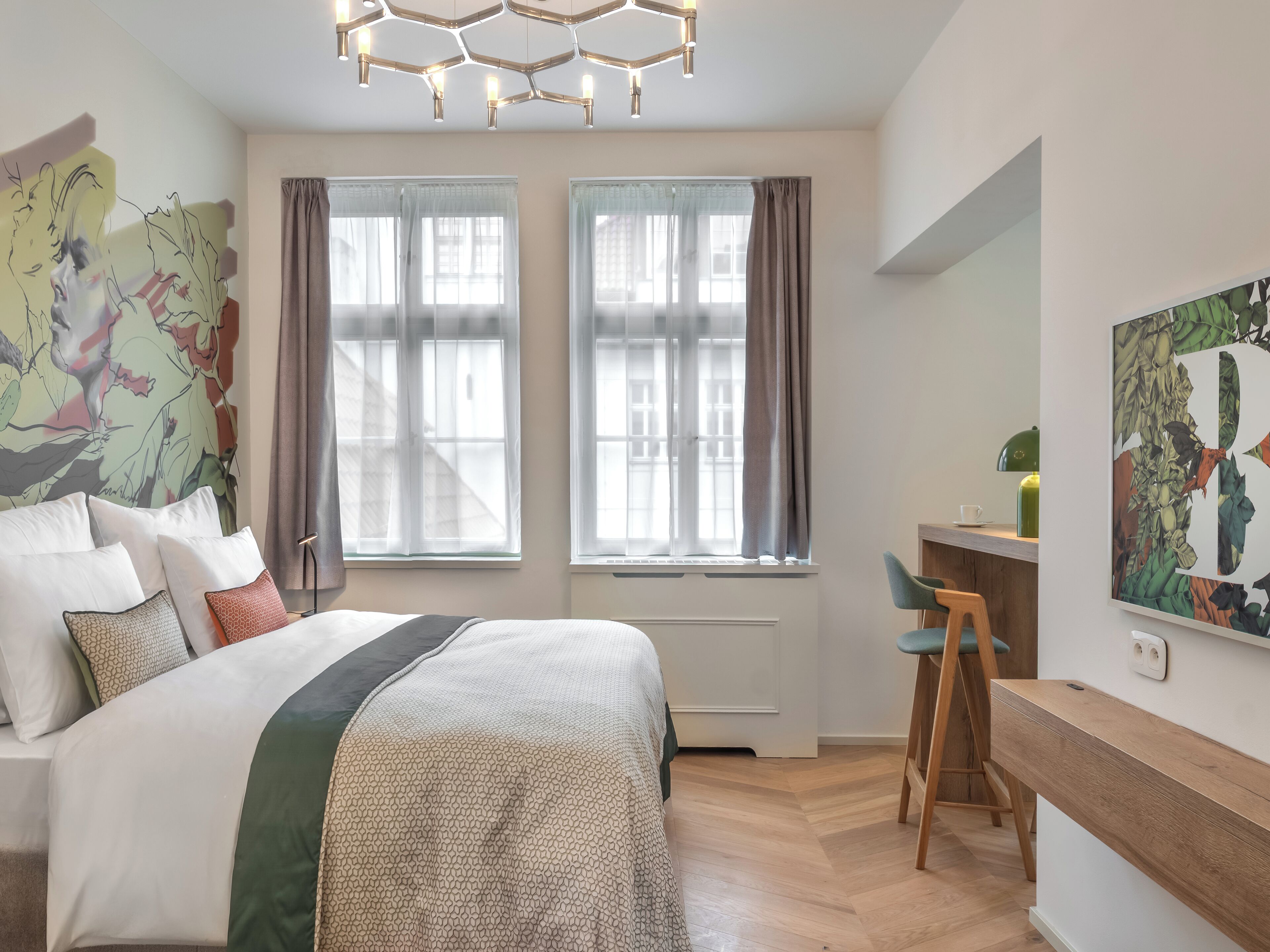 Quarto moderno com uma cama grande, duas janelas com cortinas, uma escrivaninha com cadeira e um lustre de design exclusivo.
