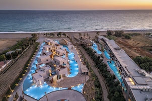 Um resort com várias piscinas, acesso à praia e vista para o oceano.