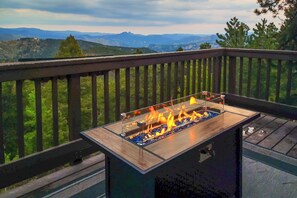 Um terraço com lareira e vista para montanhas ao longe.