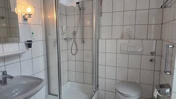 Uma casa de banho moderna com chuveiro de vidro, sanita e lavatório.