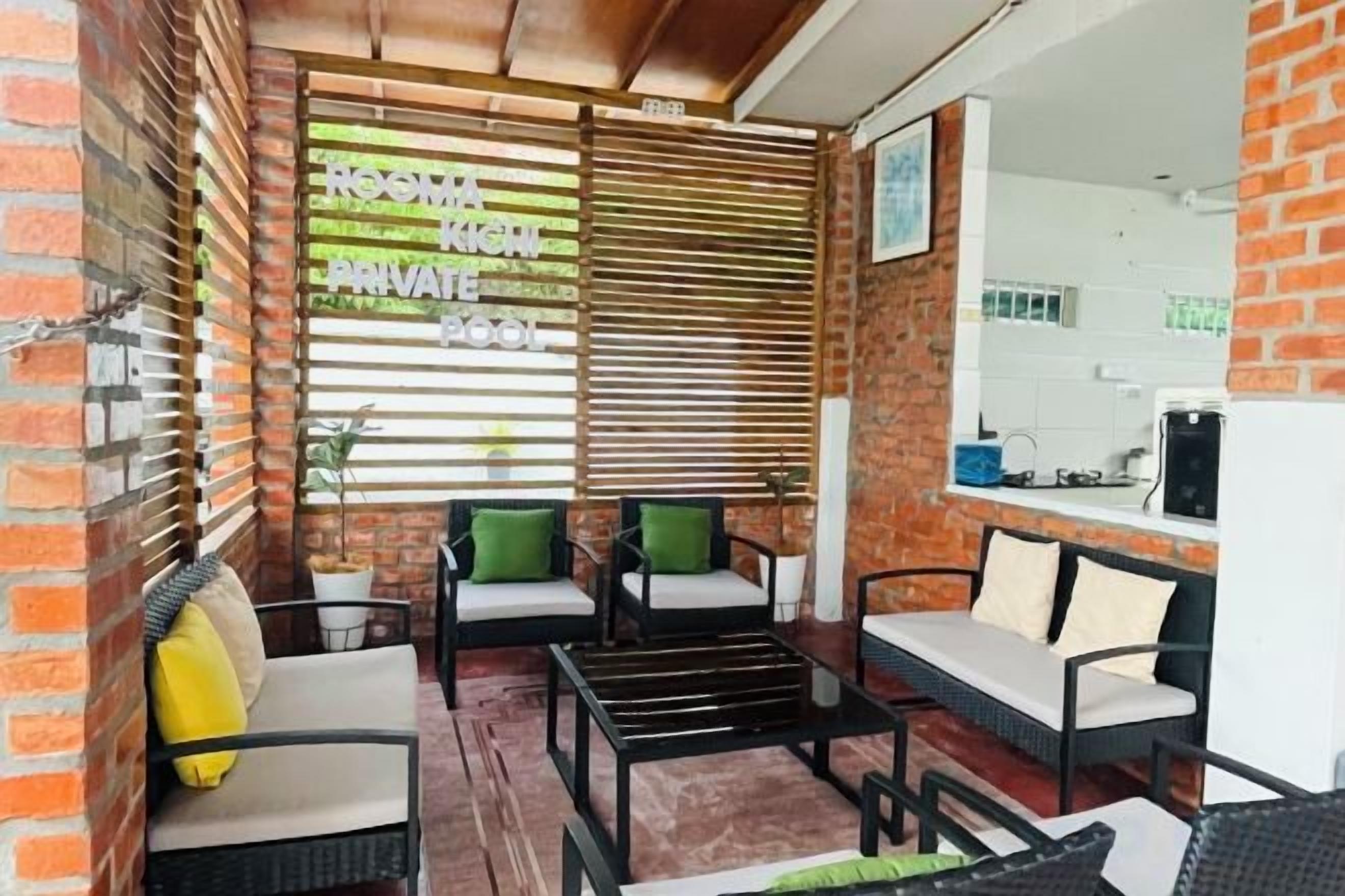 Um espaço de estar ao ar livre, pequeno e fechado, com parede de tijolos, persianas de madeira e uma kitchenette.
