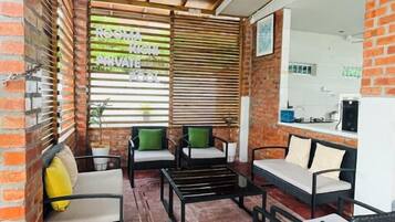 Um espaço de estar ao ar livre, pequeno e fechado, com parede de tijolos, persianas de madeira e uma kitchenette.