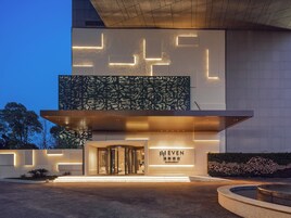 Entrada de hotel moderna com porta giratória, padrões geométricos iluminados e uma placa com a inscrição "EVEN".