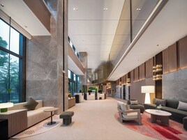 Um hall amplo com teto alto, paredes de mármore e área de estar central com sofás e mesa de centro.