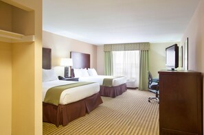 Quarto de hotel com duas camas, uma escrivaninha, uma cadeira, televisão e janela com cortinas.