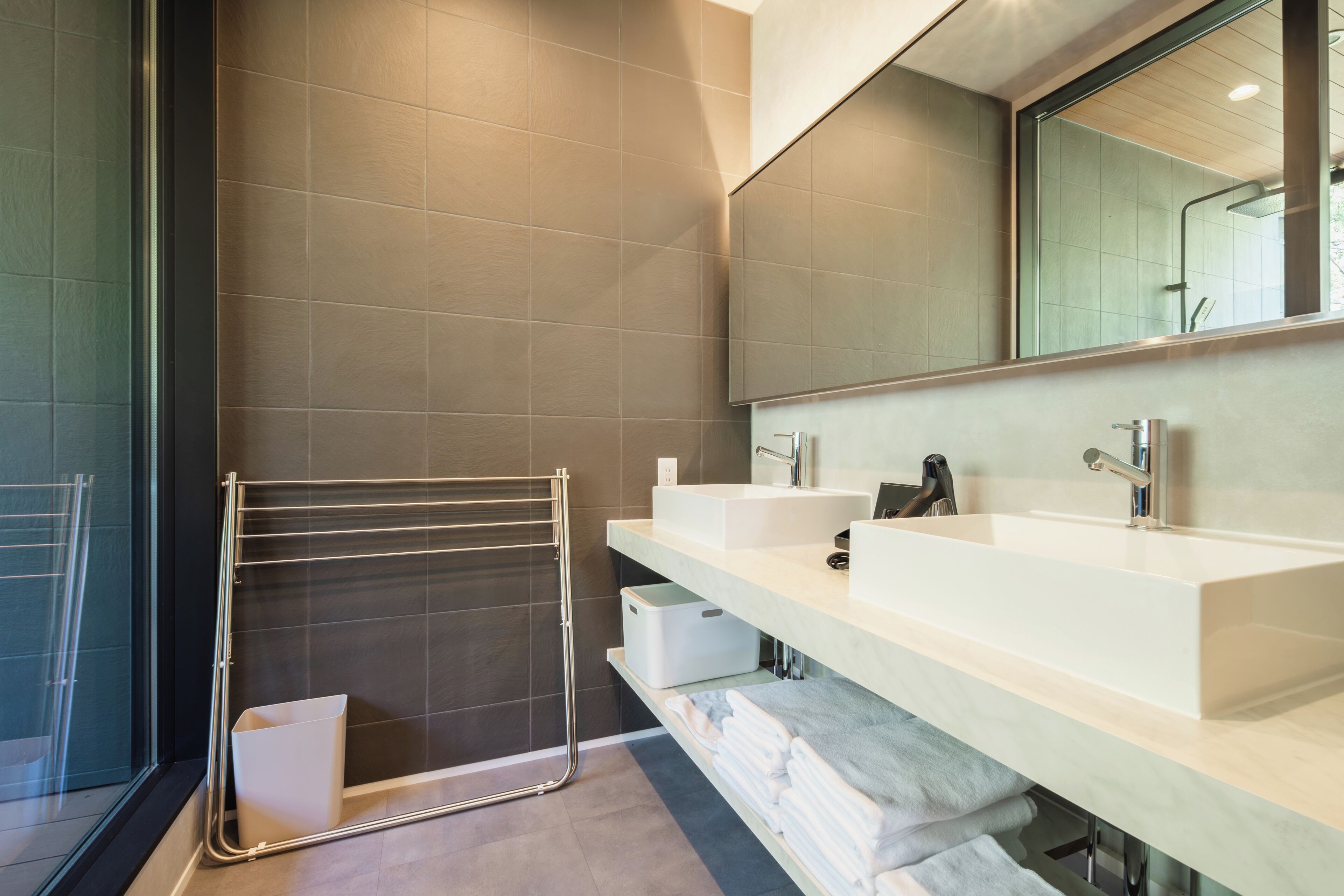 Uma casa de banho moderna com duas lavatórios, um espelho grande e um porta-toalhas.