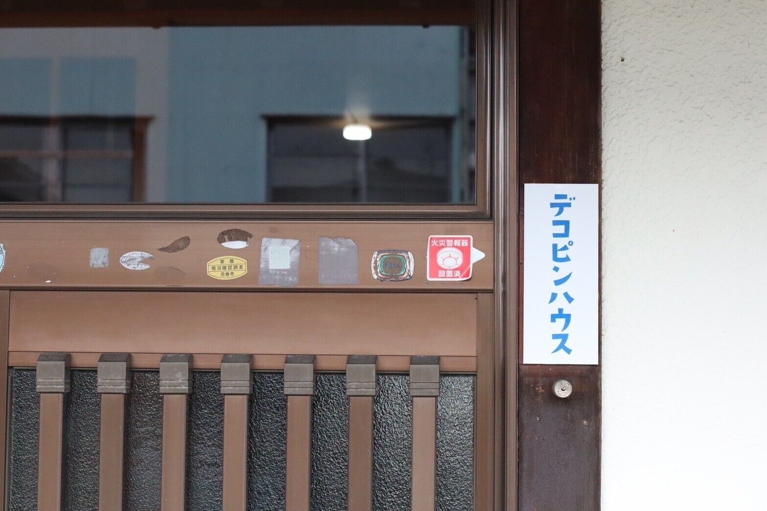 Uma porta com uma placa indicando um número de quarto e uma janela com adesivos.