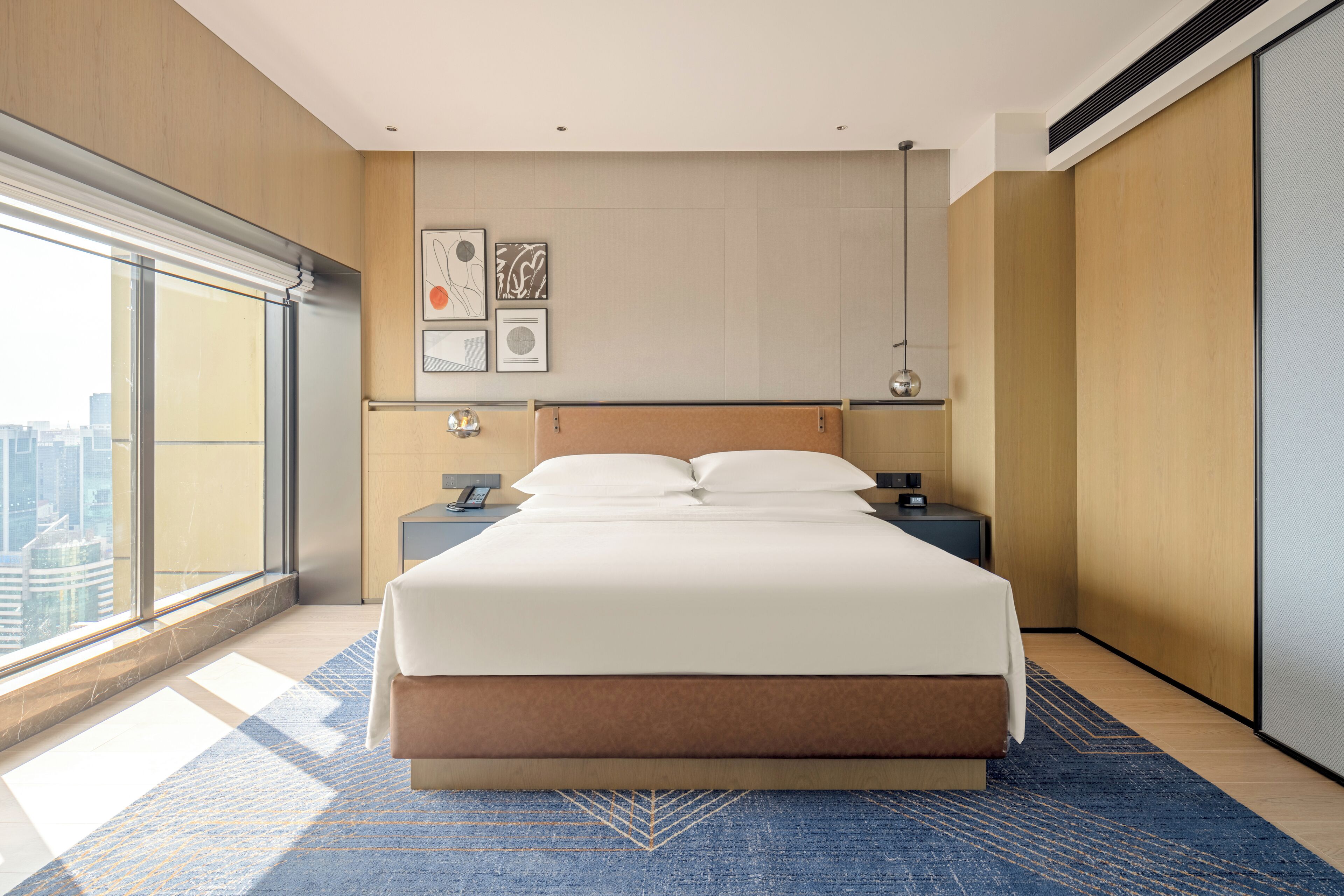 Quarto de hotel moderno com uma cama grande, vista para a cidade e decoração minimalista.