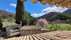 Um edifício rústico de pedra com telhado de telhas, um arco de pedra e um deck de madeira.