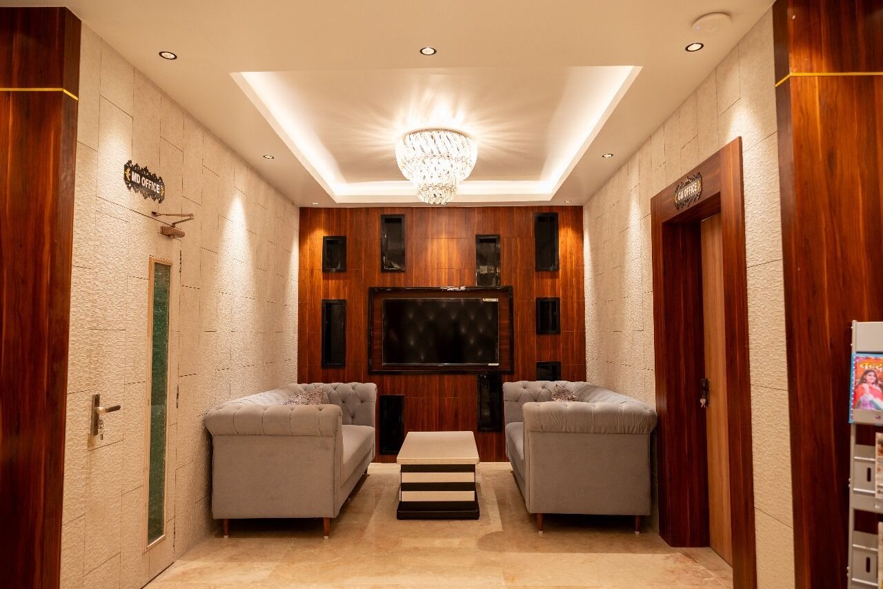 Um hall moderno com um candelabro, uma televisão de tela plana grande e dois sofás.