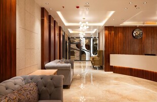 Um hall moderno com um sofá confortável, um balcão de recepção e um candelabro.