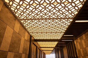 Corredor com painéis de teto estampados e piso de azulejos.