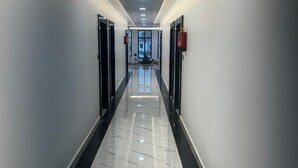 Um corredor comprido e estreito, com piso de mármore brilhante e bordas pretas.