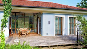 Uma casa moderna com deck de madeira, janelas amplas e um vaso com planta.