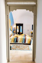 Um quarto com cama, espelho, porta e parede com design circular.