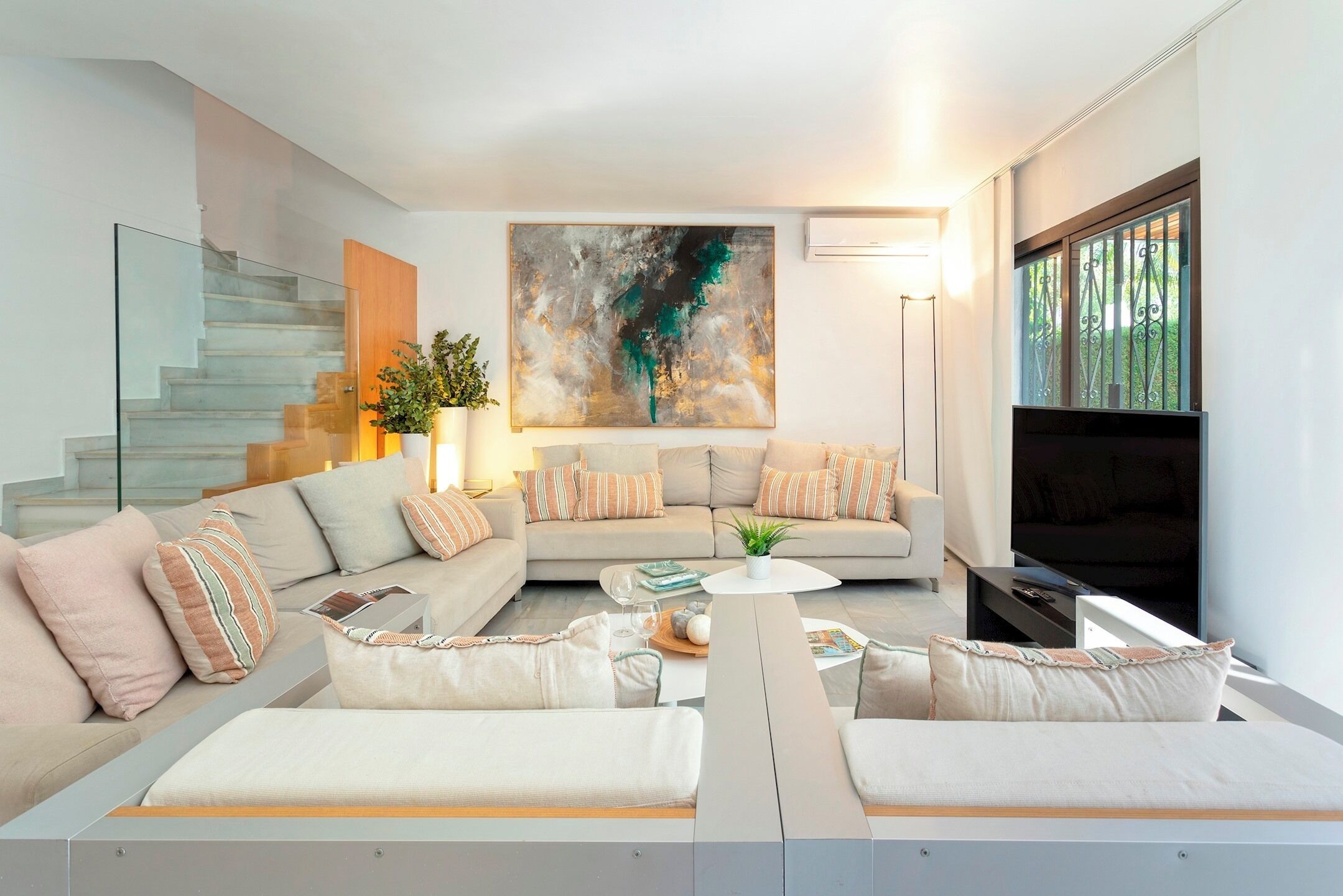 Uma sala de estar moderna com um conjunto de sofá, uma mesa de centro e uma grande pintura abstrata.