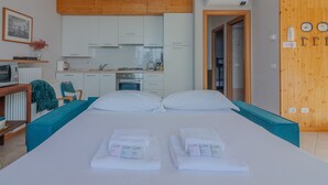 Quarto de hotel com cama, cozinha compacta e parede de madeira.