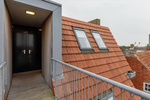 Um edifício moderno com fachada de madeira, uma porta preta e uma varanda com guarda-corpo de metal.