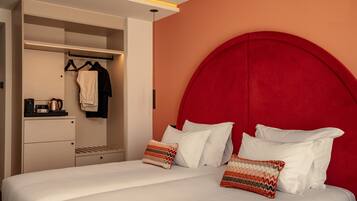Quarto de hotel com cama, um guarda-roupa e cabeceira vermelha.