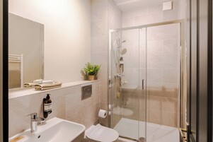 Uma casa de banho moderna com chuveiro em cabine de vidro, lavatório e sanita.