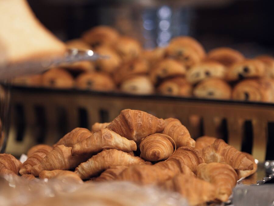 Variedade de doces, incluindo croissants, expostos.
