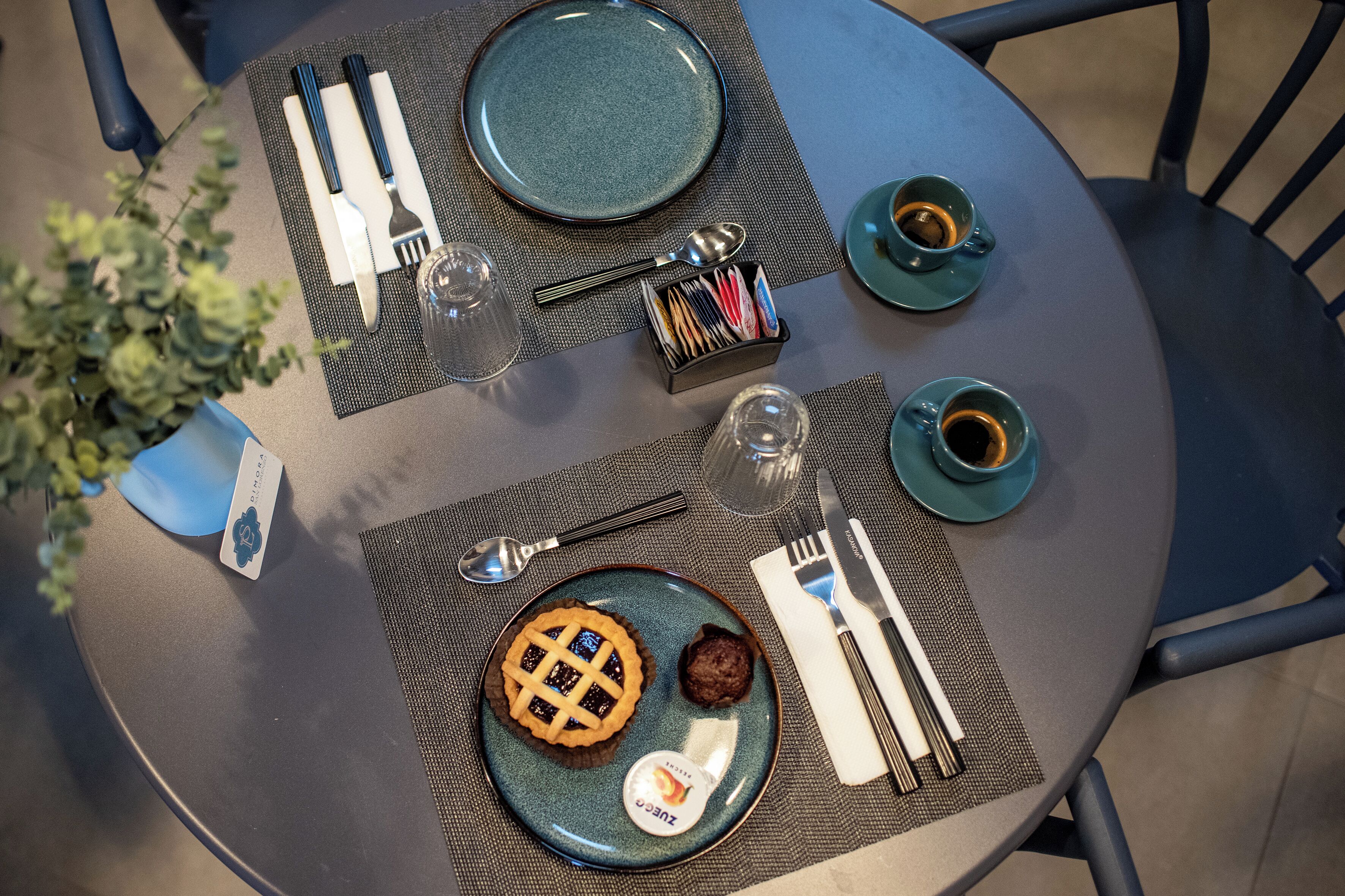 Mesa posta com um prato de comida, talheres e duas xícaras de café.