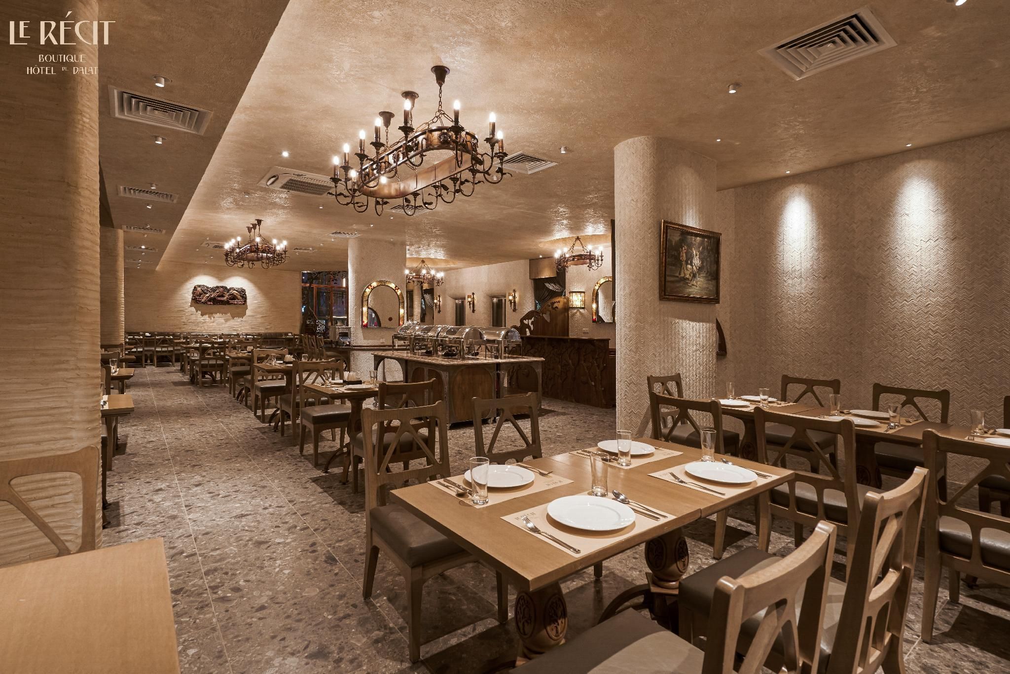 Restaurante com mesas e cadeiras de madeira, um candelabro e chão de pedra.