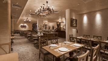 Restaurante com mesas e cadeiras de madeira, um candelabro e chão de pedra.