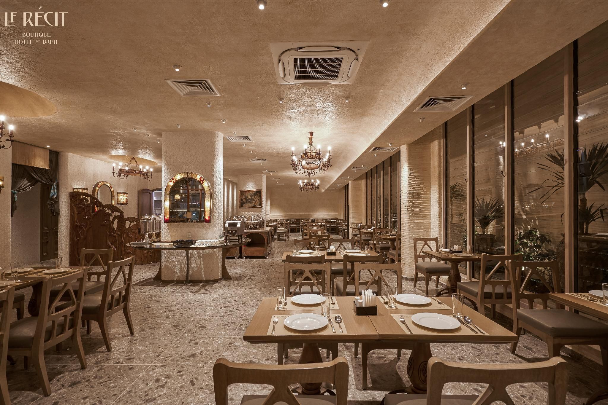 Um restaurante amplo com tetos altos, lustres e uma paleta de cores quentes. Mesas estão dispostas para refeições, e o chão é revestido com azulejos.