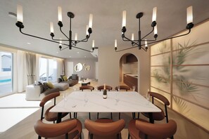 Uma área de jantar moderna com uma mesa branca, cadeiras marrons e um candelabro.