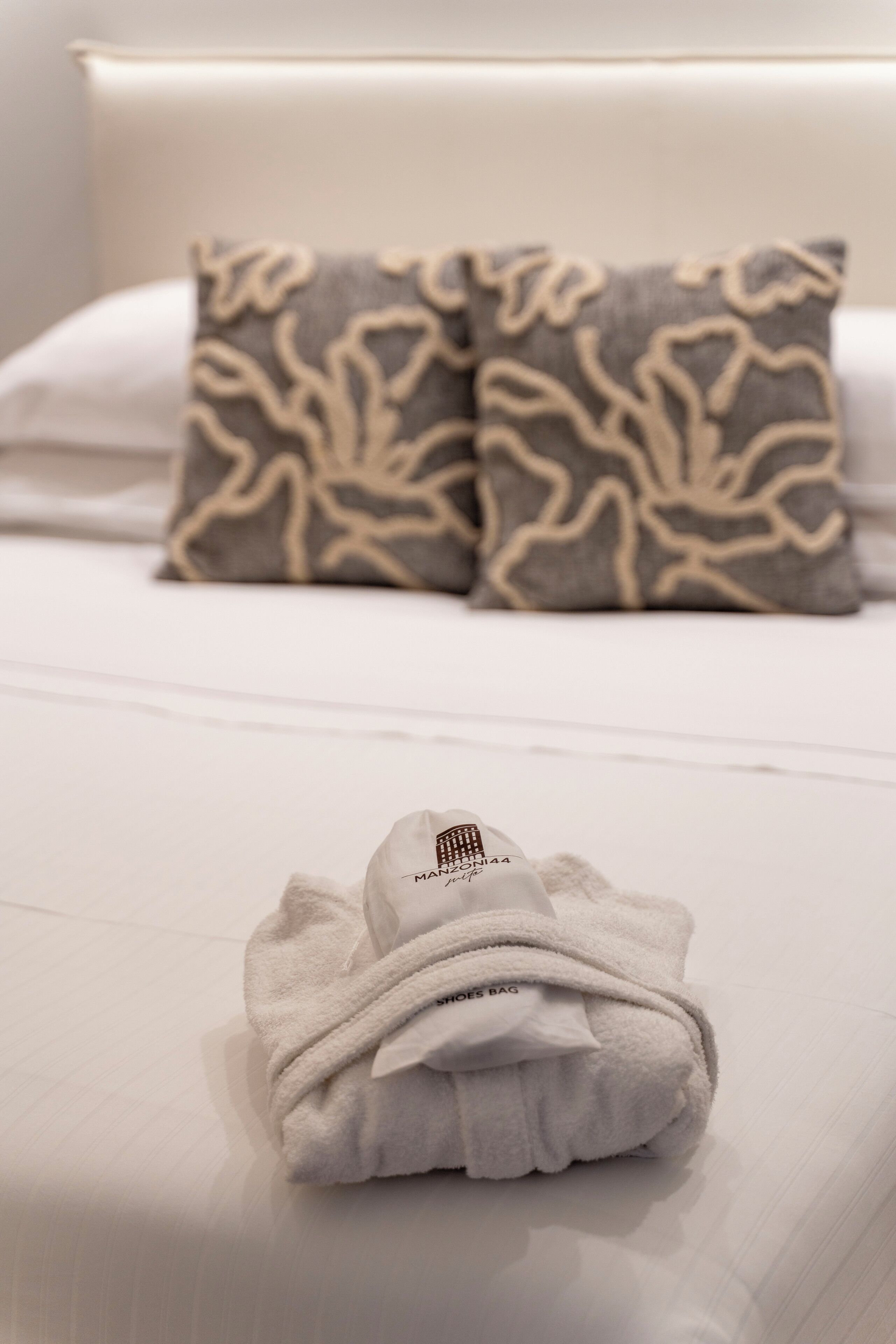 Cama bem arrumada com um cobertor branco e um par de chinelos brancos em cima.