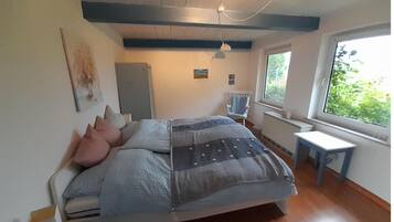 Quarto com cama, cadeira, escrivaninha, janela e radiador.