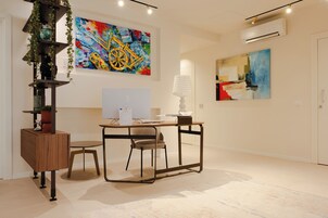 Um espaço de escritório moderno com uma mesa de madeira, duas cadeiras, uma planta em vaso e pinturas abstratas nas paredes.