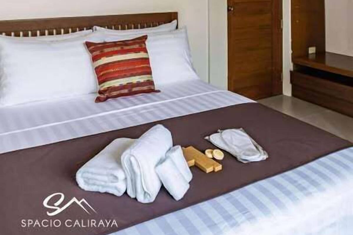 Quarto de hotel com cama, ventoinha no teto, um detalhe decorativo na parede e um guarda-roupa.