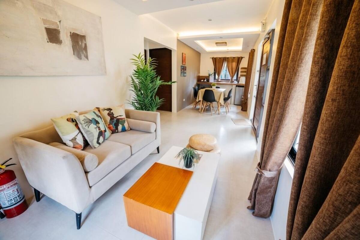 Uma sala moderna com sofá, mesa de centro e área de jantar com cadeiras.